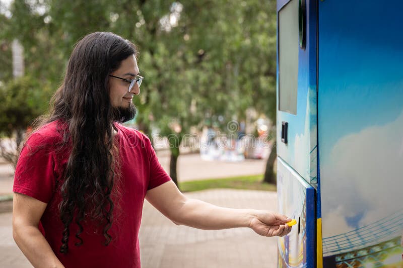 Young Hispanic Man Using Bottle Deposit Point. Man Recycling Plastic ...