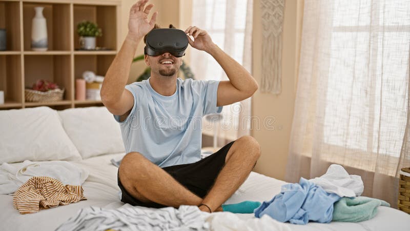Hispanic Man Using Vr Headset in a Messy Bedroom, Portraying Technology ...