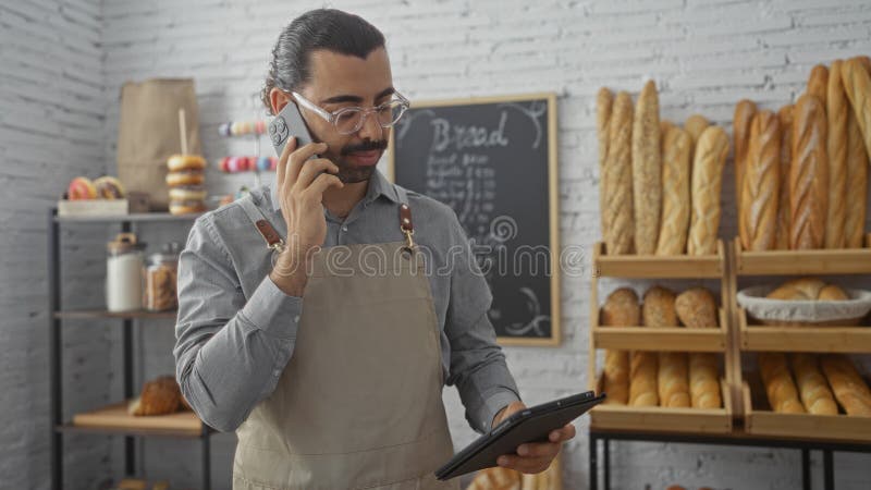 Hispanic Man Working in a Bakery Talking on the Phone while Holding a ...