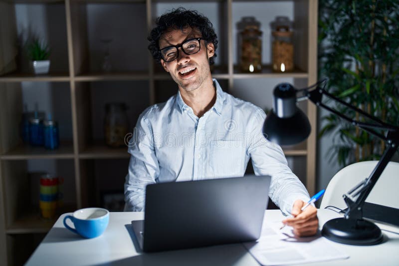 Hispanic Man Working at the Office at Night Winking Looking at the ...
