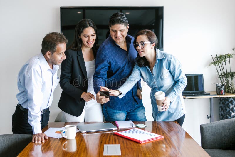 Hispanic Office Workers Looking at a Smartphone in the Office in Latin ...