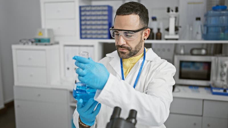 Hispanic Scientist Man Examining a Blue Liquid in a Flacon Inside a ...