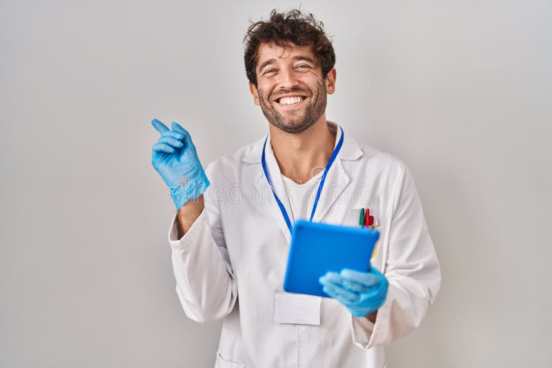 Hispanic Scientist Man Working with Tablet Smiling Happy Pointing with ...