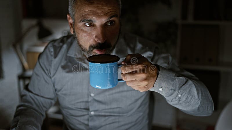 Hispanic Senior Man with Grey Beard Drinking Coffee Indoors at Office ...