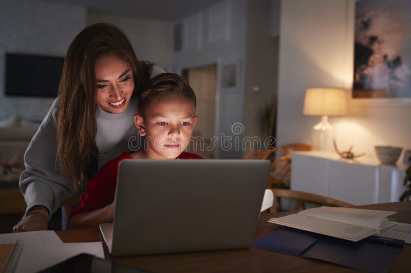 Hispanic Woman Looking Over Her Sonï¿½s Shoulder while he Does His ...