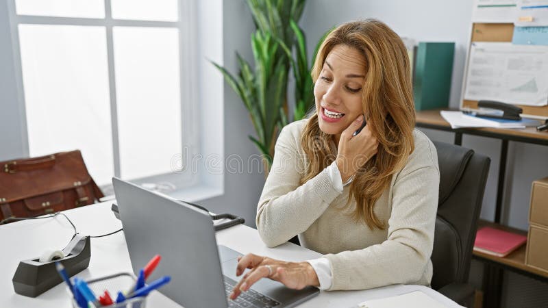 Hispanic Woman Multitasking in a Modern Office, Talking on the Phone ...