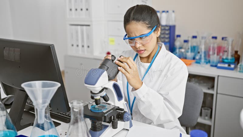 Hispanic Woman Scientist Using Microscope in a Laboratory Setting ...