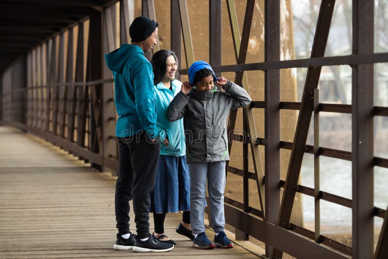 Hispanic Woman and Sons Look Out Over River from Bridge Stock Image ...