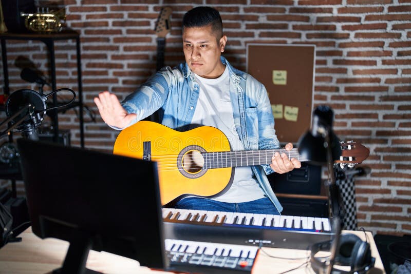 Hispanic Young Man Playing Classic Guitar at Music Studio Doing Stop ...