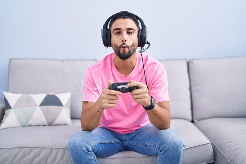 Hispanic Young Man Playing Video Game Holding Controller Sitting on the ...