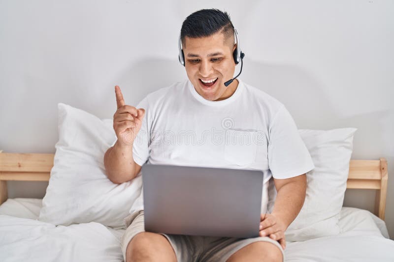 Hispanic Young Man Using Computer Laptop on the Bed Smiling Happy ...