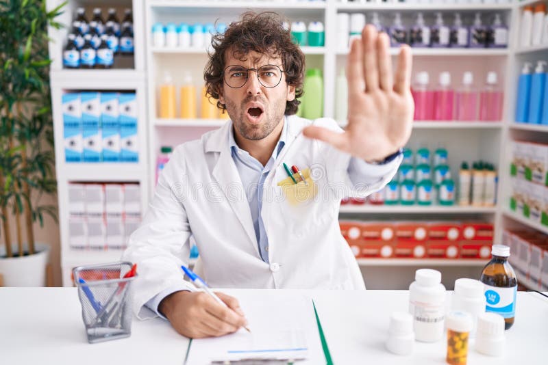 Hispanic Young Man Working at Pharmacy Drugstore Doing Stop Gesture ...
