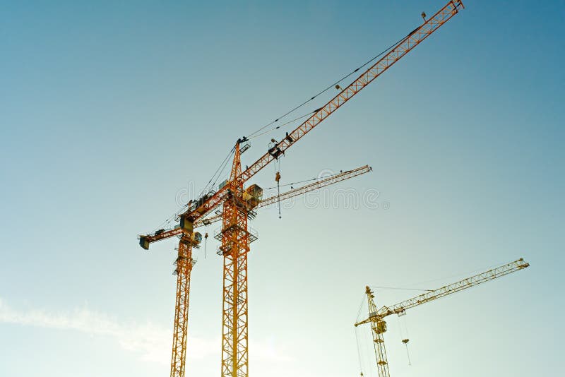 Hoisting Construction Cranes on Construction Site Against Blue Sky ...