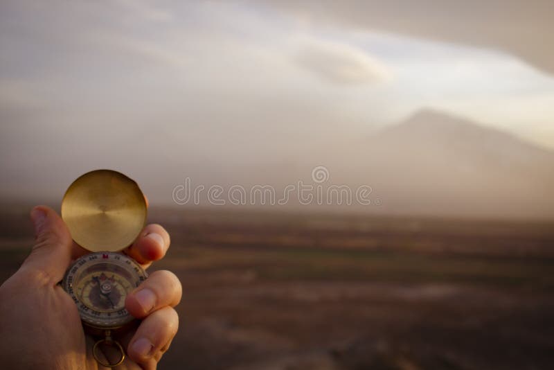 Holding a Compass Against the Backdrop of a Mountain at Sunset Stock ...