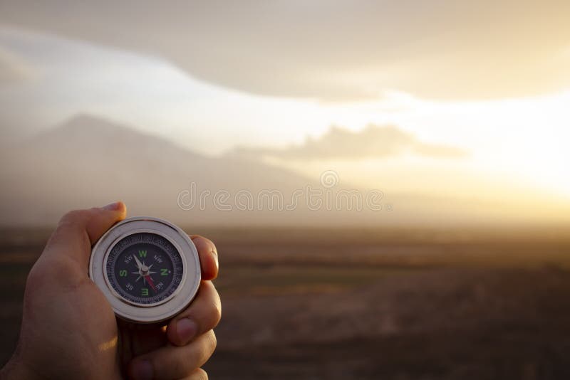 Holding a Compass Against the Backdrop of a Mountain at Sunset Stock ...