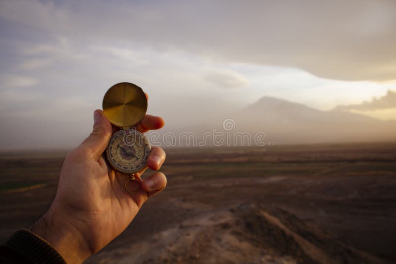 Holding a Compass Against the Backdrop of a Mountain at Sunset Stock ...