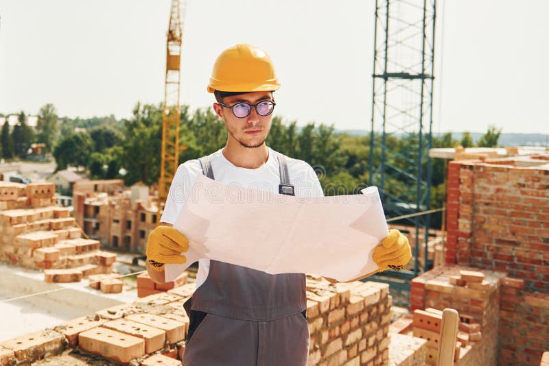 Holding Document. Young Construction Worker in Uniform is Busy at the ...