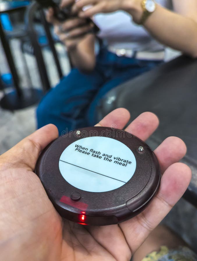 Holding an Electronic Restaurant Pager, Also Known As a Buzzer or ...