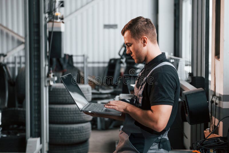 Holding Laptop in Hands. Man in Uniform is Working in the Auto Service ...