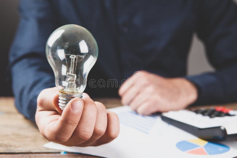 Holding a Light Bulb and Counting with a Calculator Stock Photo - Image ...