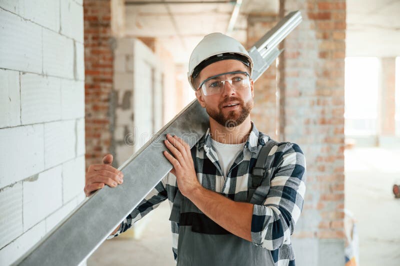 Holding Metal Plank. Construction Worker in Uniform in Empty Unfinished ...