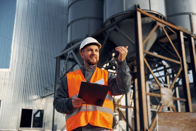 Holding Notepad in Hands. Construction Worker in Uniform is Outdoors ...
