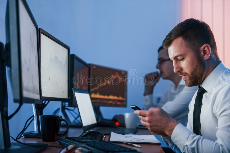 Holding Smartphone in Hands. Two Stock Traders Working in the Office ...