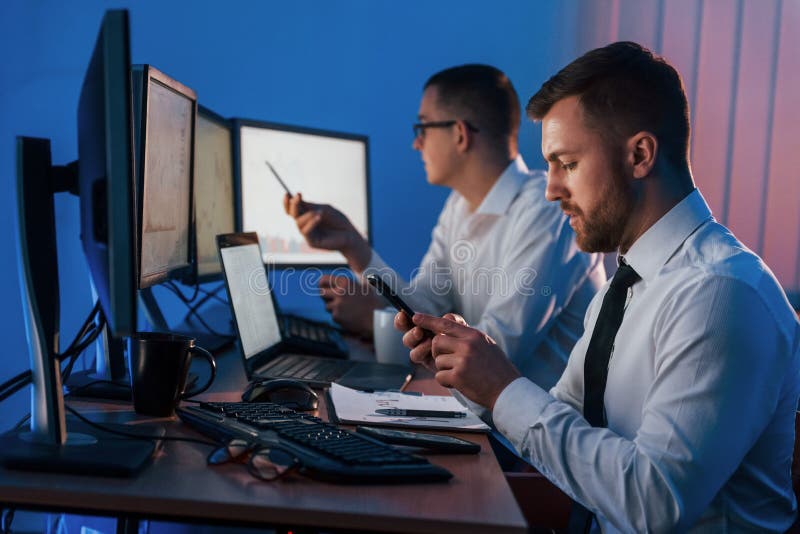 Holding Smartphone in Hands. Two Stock Traders Working in the Office ...