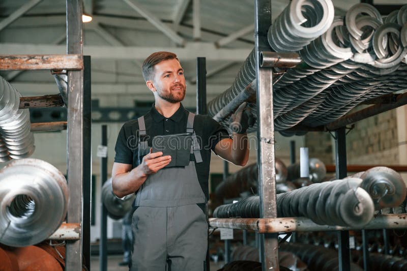 Holding Tablet. Man in Uniform is in Workstation Developing Details of ...