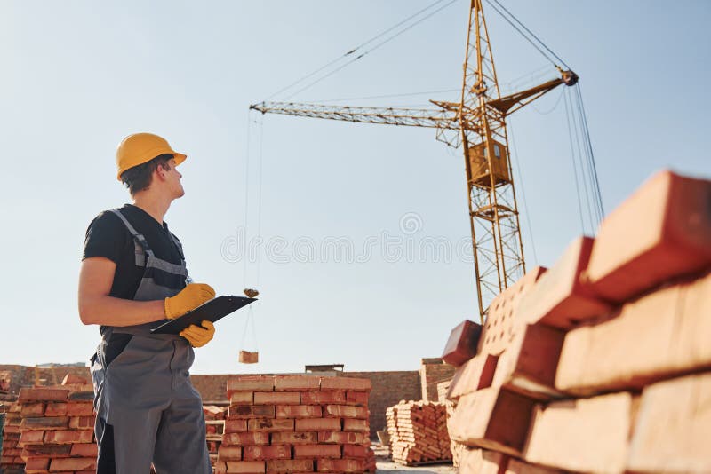 Holds Notepad with Documents. Construction Worker in Uniform and Safety ...