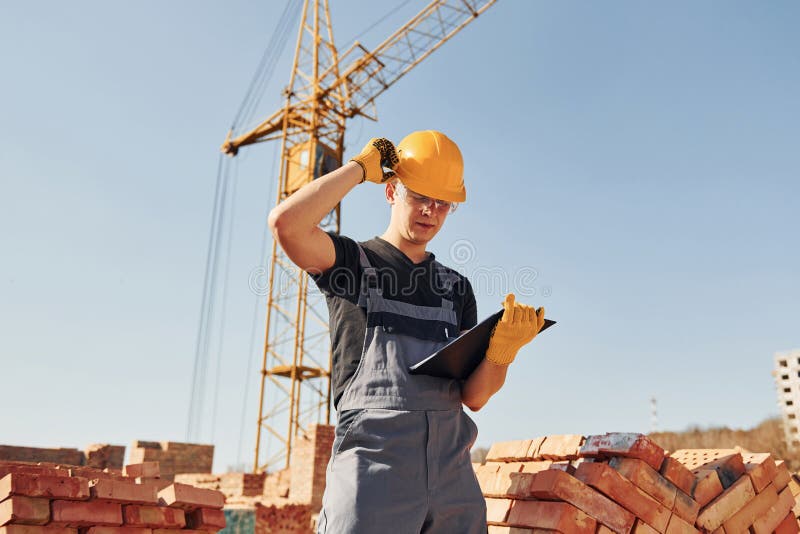 Holds Notepad with Documents. Construction Worker in Uniform and Safety ...