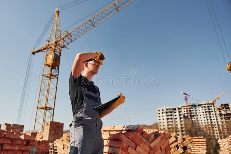 Holds Notepad with Documents. Construction Worker in Uniform and Safety ...