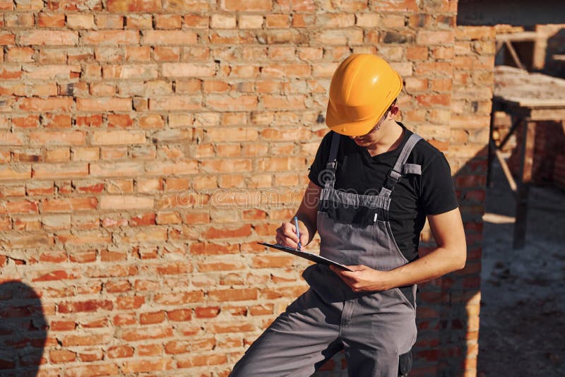 Holds Notepad with Documents. Construction Worker in Uniform and Safety ...