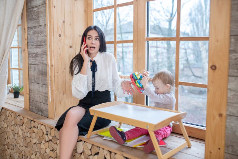 Mom Playing Learning Game with Daughter on Windowsill, Talking on Phone ...