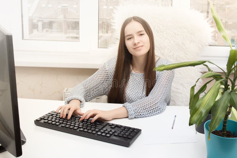 Home Office. Young Girl Sits at a Table, Typing on a Computer, Smiling ...