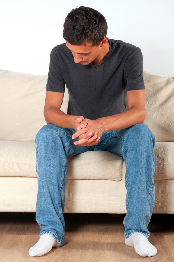 Sad Young Man Sits on a Sofa with His Head Down Stock Photo - Image of ...