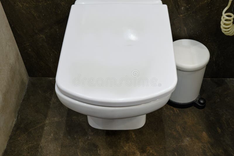 Home Toilet Closed with a White Lid and a Trash Can on the Floor Stock ...