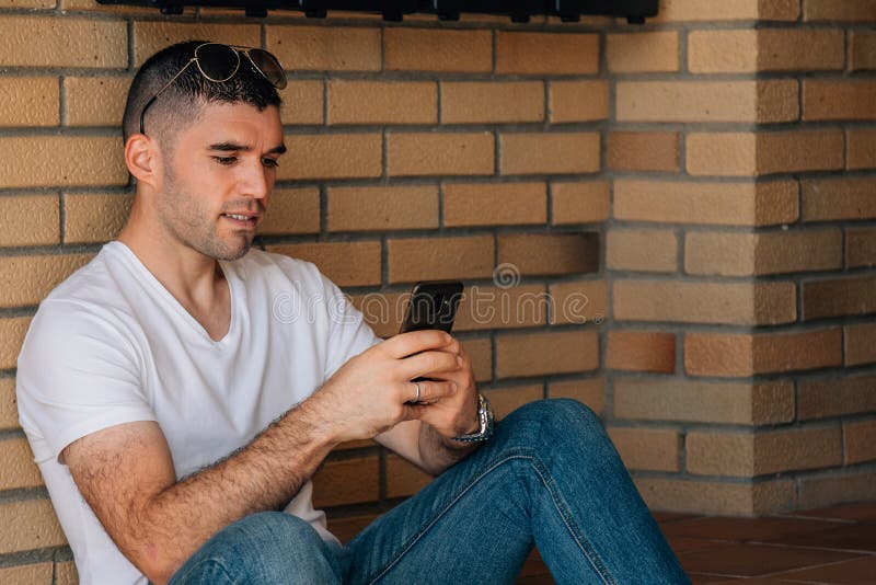 Homem na rua sentado foto de stock. Imagem de roupa - 256049766