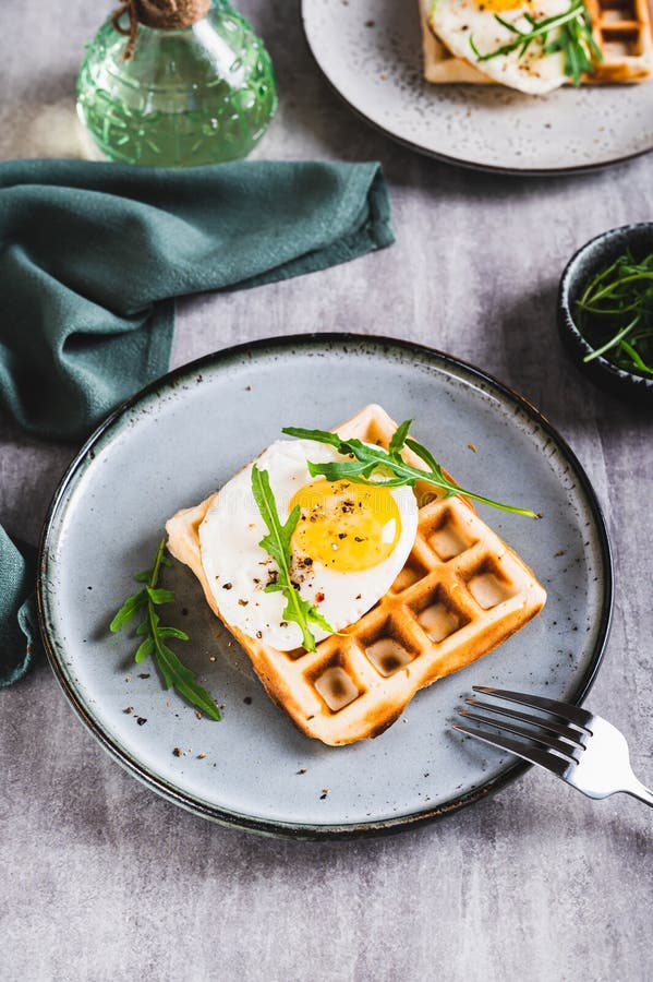 Homemade Crispy Waffles with Egg and Arugula on a Plate on the Table ...