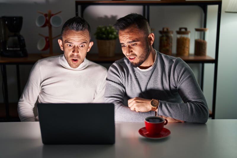 Homosexual Couple Using Computer Laptop in Shock Face, Looking ...