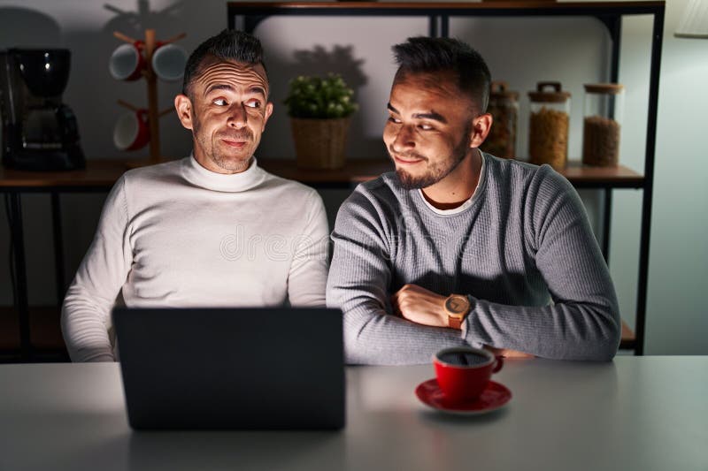 Homosexual Couple Using Computer Laptop Smiling Looking To the Side and ...