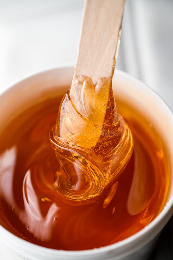 Honey-brown Sugaring Paste in a White Plastic Container with a Wooden ... Honey-brown Sugaring Paste in a White Plastic Container with a Wooden ...