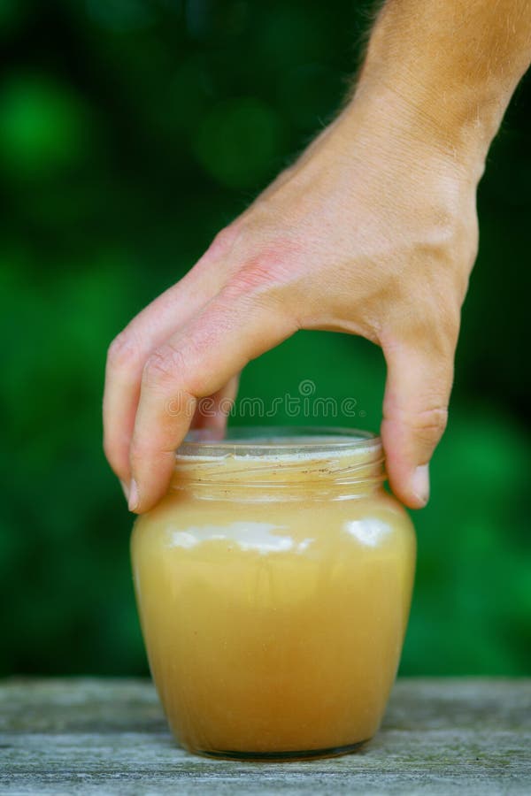 Honey in a jar in hand stock photo. Image of dipper - 253947370