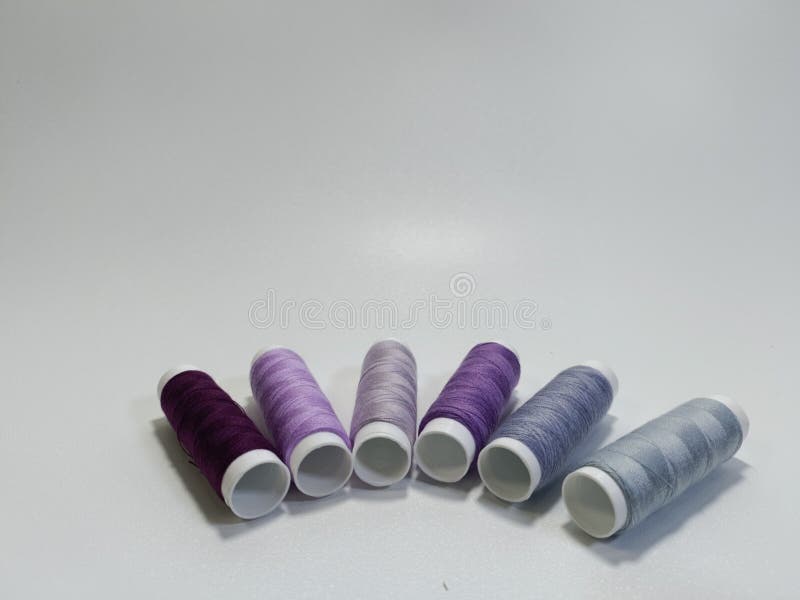 Horizontal Arrangement of Purple and Gray Sewing Thread Spools on White ...