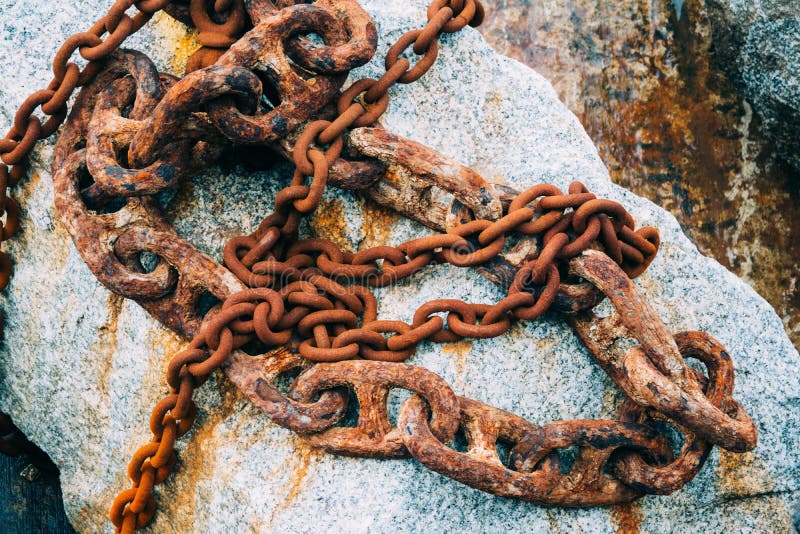 Horizontal Shot of Many Rusted Chains of Different Sizes on a Big Stone ...