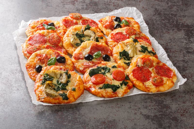 Hot Assorted Mini Pizza Or Pizzette With Various Toppings Close Up On Parchment Horizontal