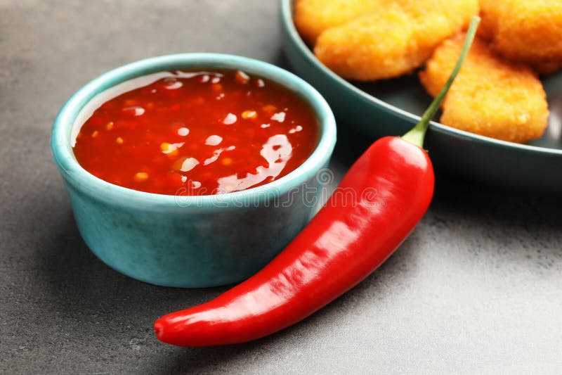 Hot Chili Sauce in Bowl and Pepper on Grey Textured Table, Closeup ...
