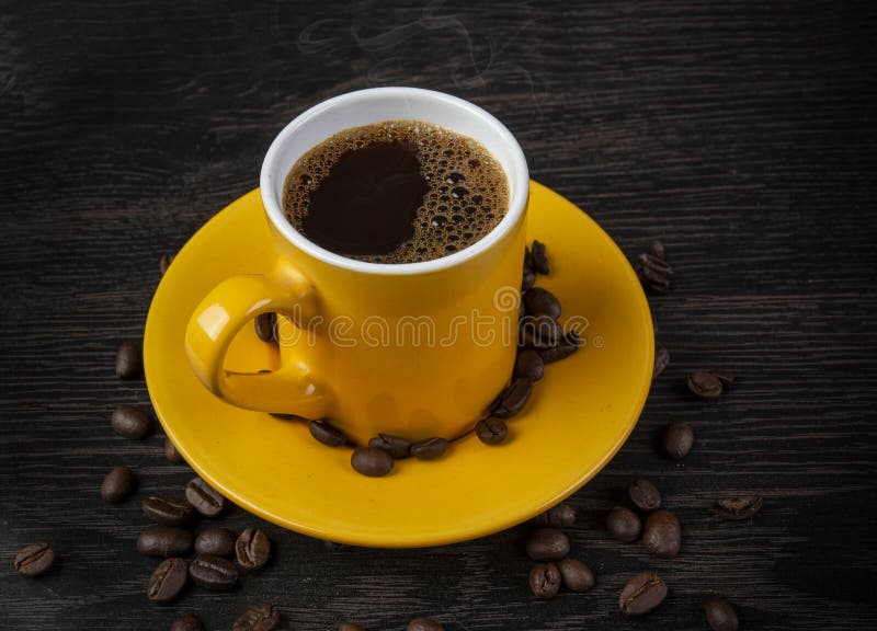 Hot Coffee in Yellow Cup with Coffee Beans on Dark Back Table Stock ...