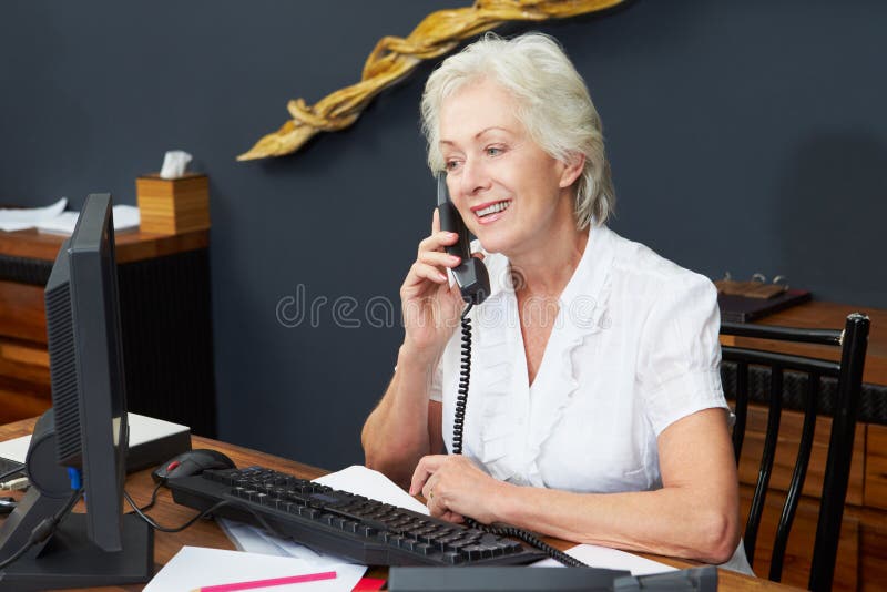 Hotel Receptionist Using Computer and Phone Stock Photo - Image of ...