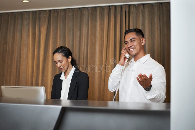 Hotel Receptionists Engaged in Work Tasks at a Modern Hotel Front Desk ...